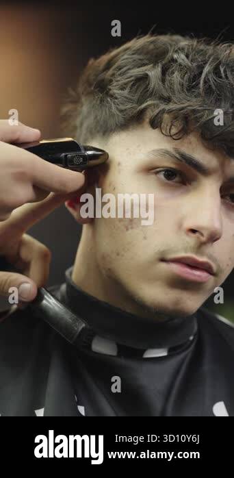 Close up of a barber using an electric razor for a stylish fade haircut ...