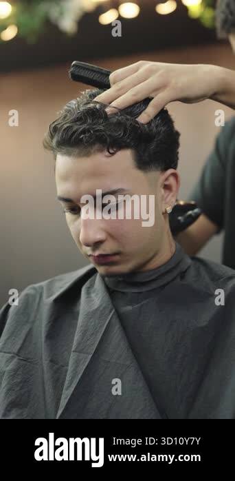 Slow motion closeup of a barber using a comb to style a young mans ...