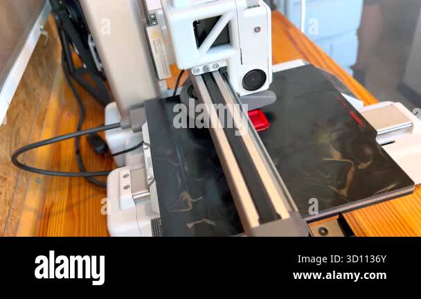 Modern 3d printer adding material layers to create a small red object ...
