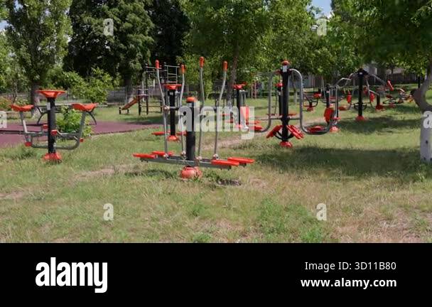 Fitness equipment displayed in a park setting, featuring colorful machines designed for outdoor ...