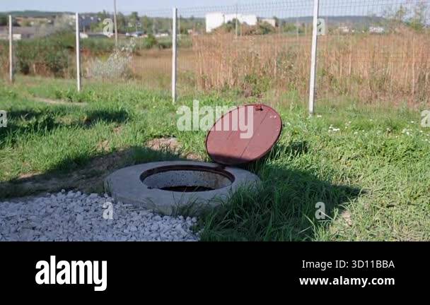 Open sewer manhole cover displays a circular opening surrounded by ...