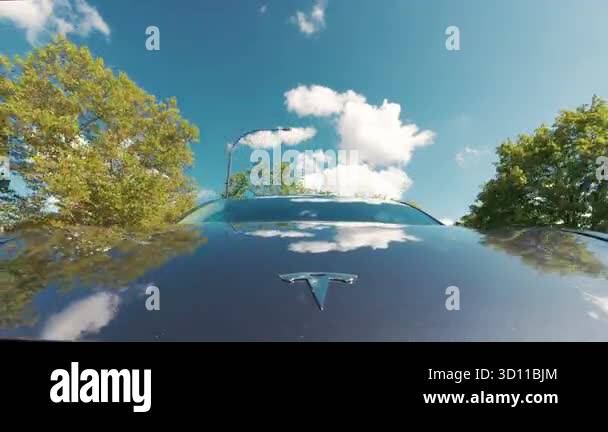 Tesla car roof and hood reflecting a blue sky with white clouds and ...