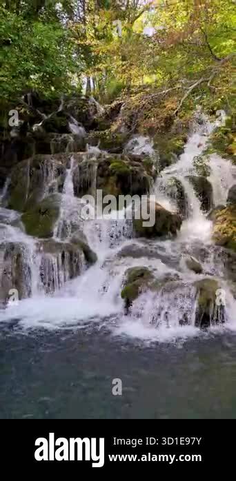 Pull back drone footage showing waterfall fading into wide forest view ...
