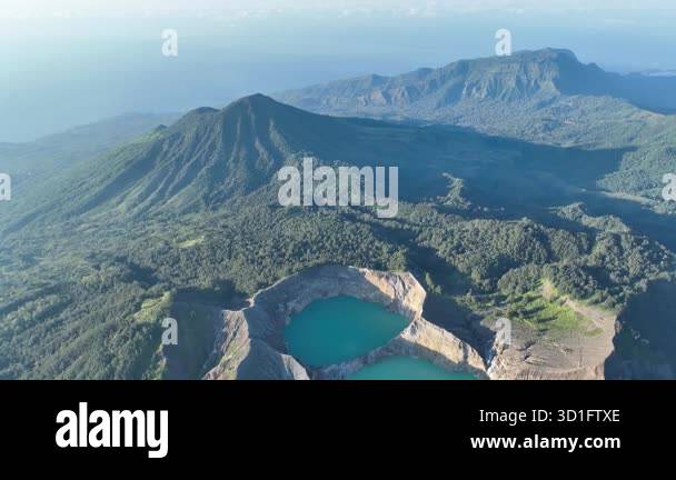 Mount Kelimutu rises dramatically above the forest canopy, guarding the ...