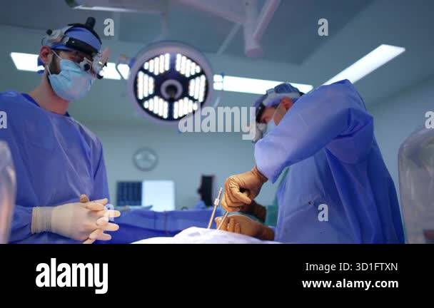 Neurosurgeon uses metal medical tools at operation. Low angle view at ...