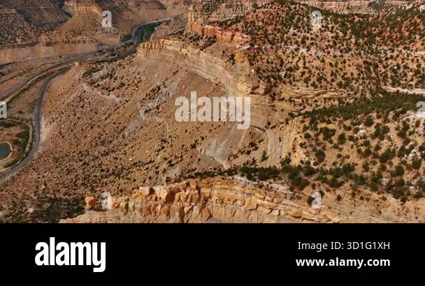 Flying over the canyons covered with small bushes. Cars ride by the ...