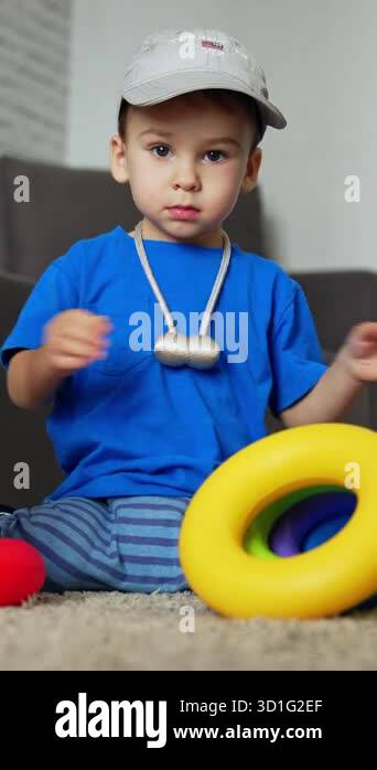 Beautiful Caucasian toddler sits on the floor waving his hands from ...