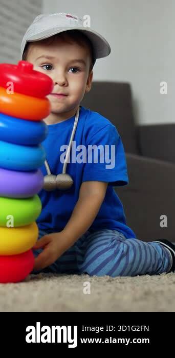 Adorable toddler kid throws his colorful pyramid on the floor. Baby boy ...