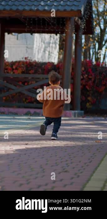 Rear view of a little toddler running outdoors. Happy energetic baby ...