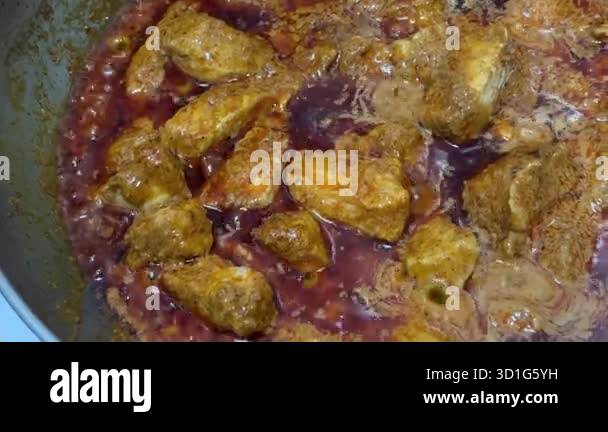 A close-up footage of boiling Thai curry with chunks of meat immersed ...