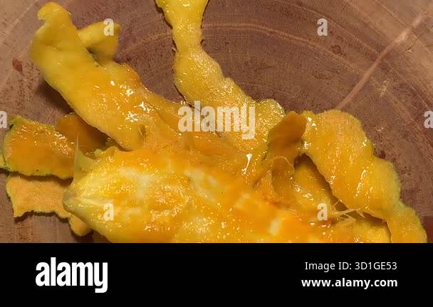 4K footage of freshly peeled mango flesh on a wooden board, showing ...