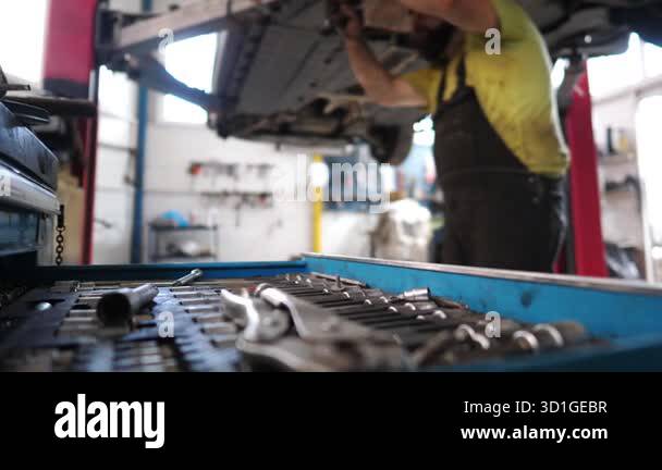 Mechanic performing car repair in a busy auto service garage ...