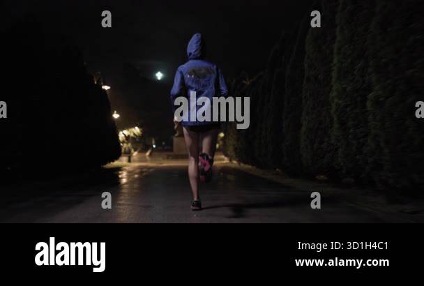 A lone runner in a park at night, enjoying a peaceful jog along wet ...