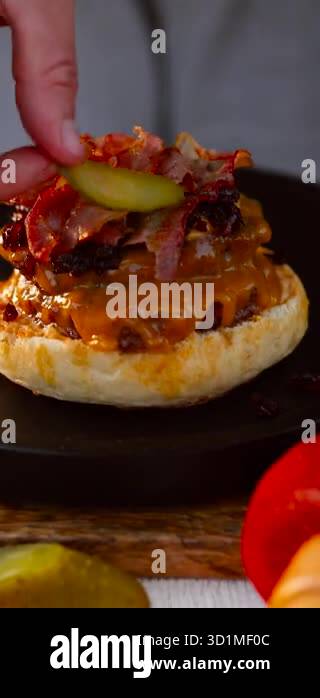 Vertical video of homemade grilled burger being assembled with sauce ...