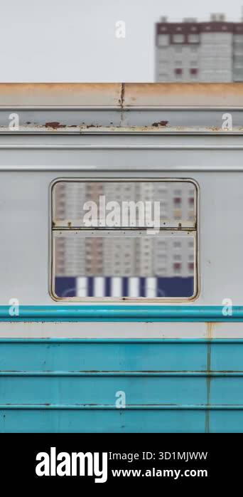 An old moving train carriage window with rusty details and blured city ...
