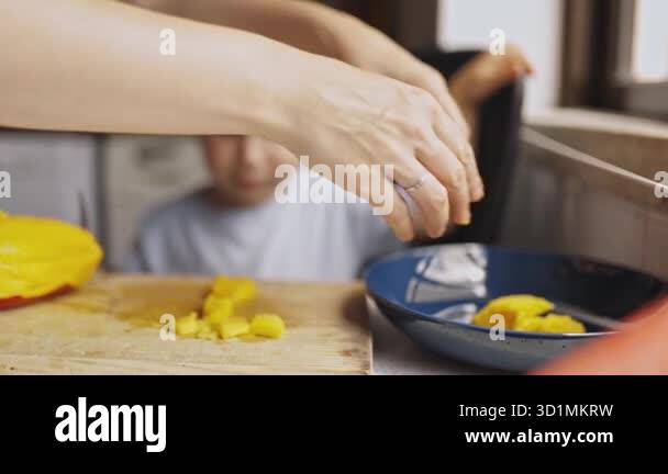 Mothers hands cutting fresh ripe mango fruit for her child sitting at ...