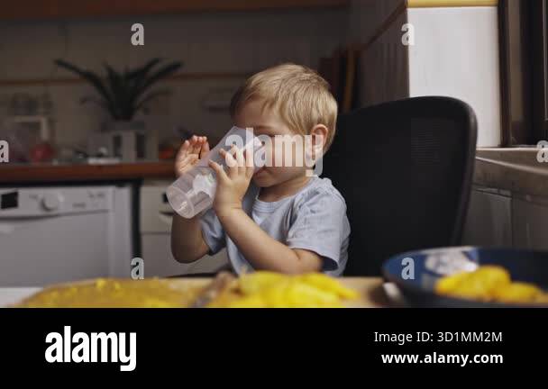 Cute little blond boy drinking water and feeling mischievous while ...