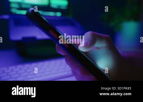 Close up of hand browsing content on a mobile phone in front of a desk ...