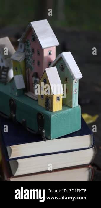 Whimsical wooden miniature houses adorn a book stack, creating a ...