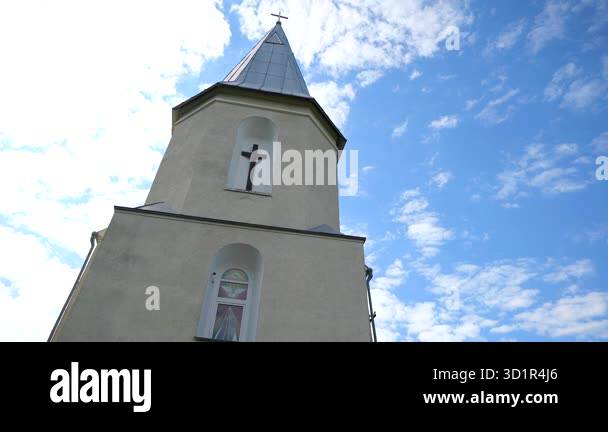 A church steeple pierces the bright blue sky, adorned with fluffy white ...