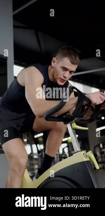 Focused young man with a serious expression cycling hard on a ...