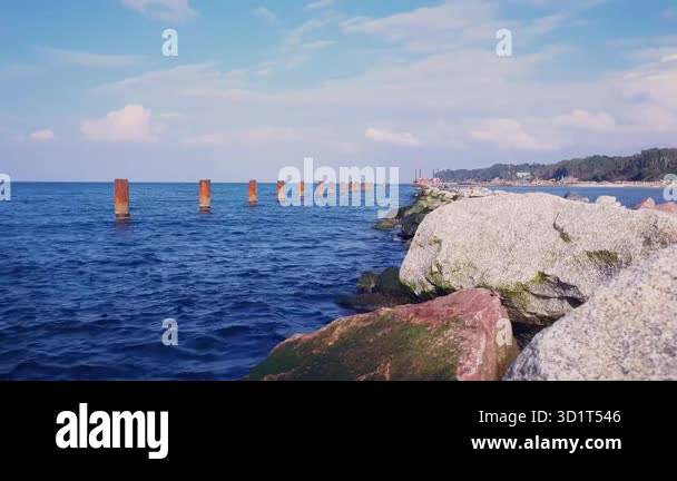 Calm sea waves water surface and stone embankment by huge boulders ...