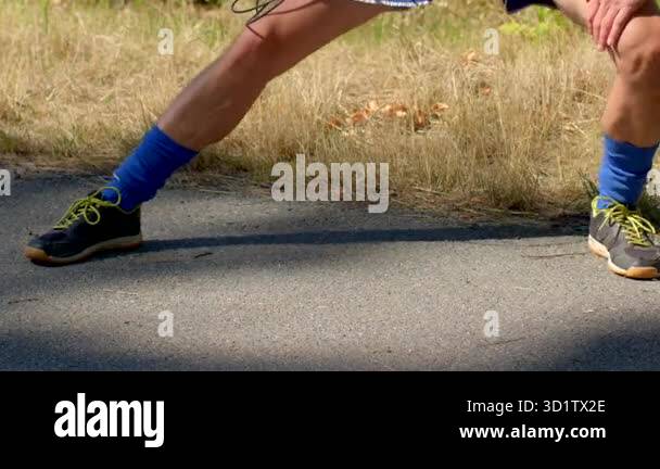 An athlete stretches their leg while tying a jump rope outdoors ...