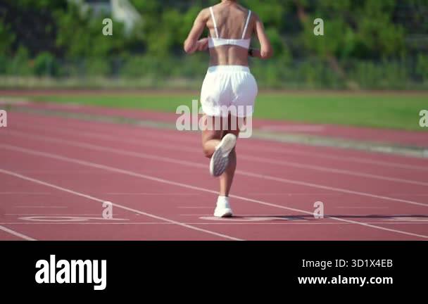Morning jog motivation, sporty woman runs at a stadium track on a sunny ...