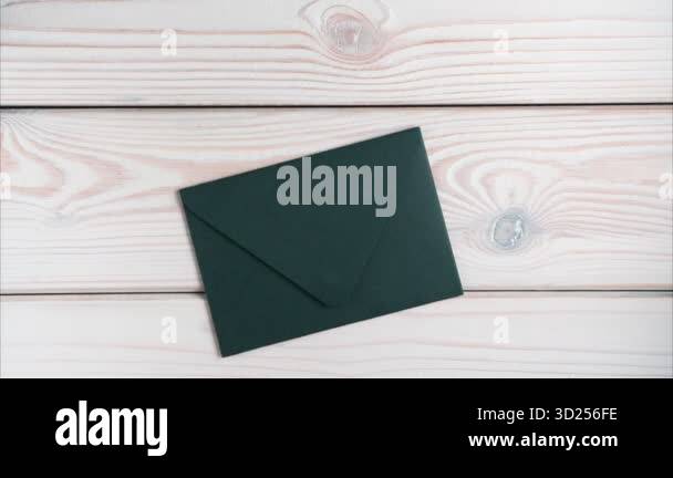 Closed green envelope appearing on grey wooden table, opening. Hundred ...