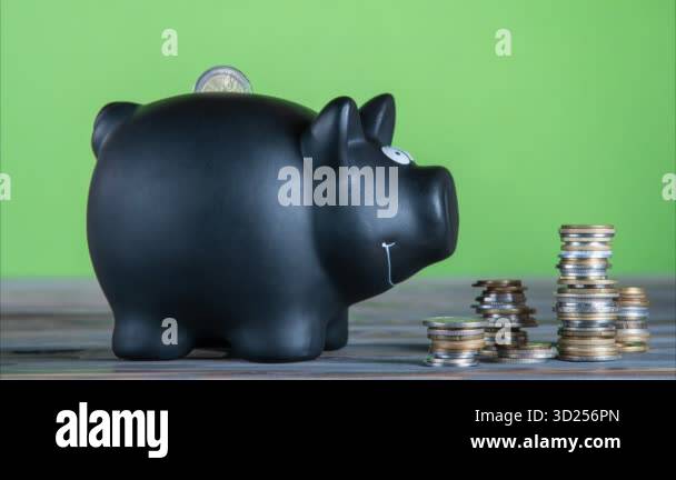 Side view of black smiling piggy bank near stacks towers of coins on ...
