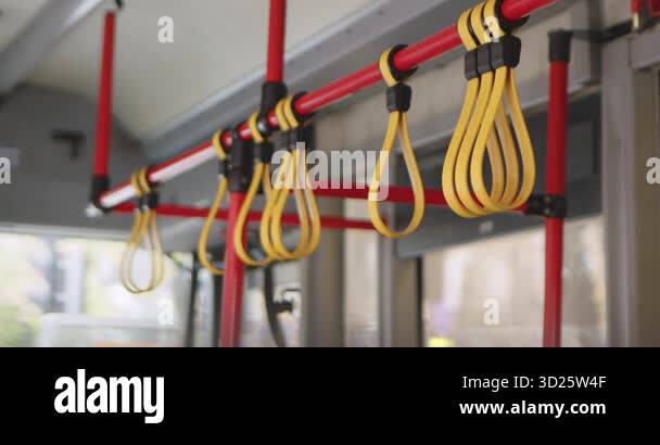 Close up of yellow hand grips on red poles inside a public bus ...