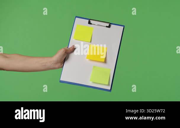 A woman hand holding a clipboard with yellow sticky notes on a green ...