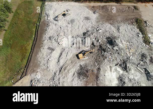 Demolition site, with excavators working on a large area of debris and ...