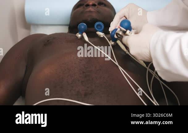 A doctor attaches ECG sensors to a patients chest. An ECG procedure in ...
