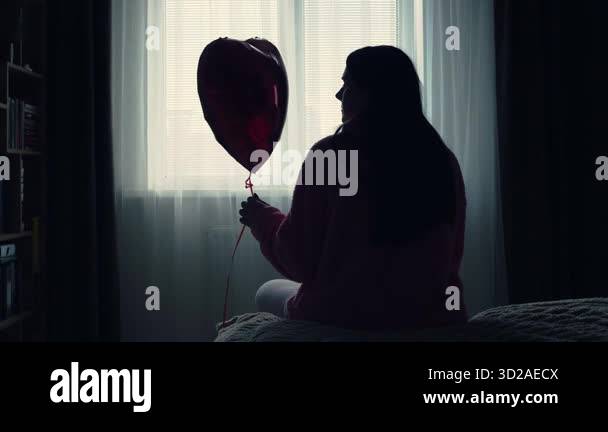 Silhouette of a sad and depressed woman sitting alone in a dark room ...