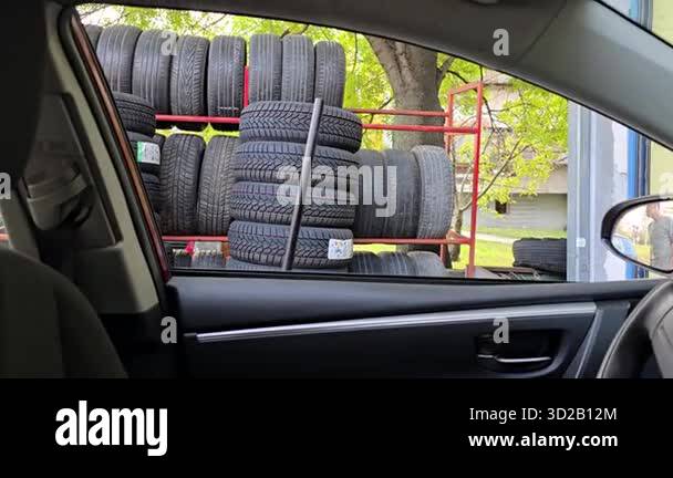 View from inside a car at a tire service, showing stacks of new tires ...