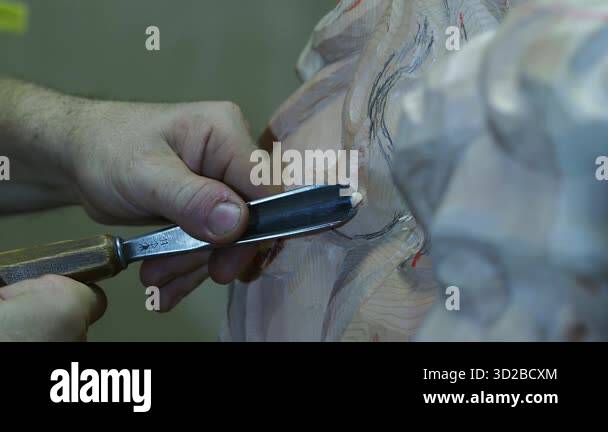 Extreme close up of sculptor hand using chisel to carve and refine ...