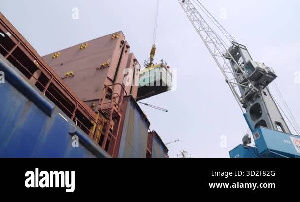 ALMATY, KAZAKHSTAN - OCTOBER 09 2025: Tower crane lifts heavy container ...