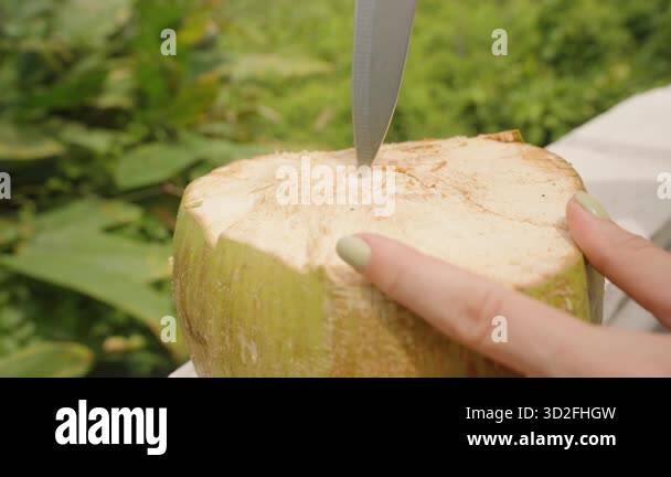 Close-Up of a Knife Piercing a Fresh Green Coconut Outdoors in Natural ...