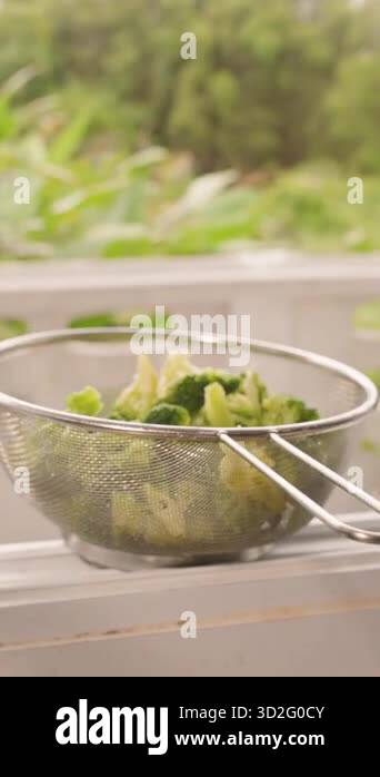 Vertical video. Colander Filled with Steamed Broccoli Resting on Open ...