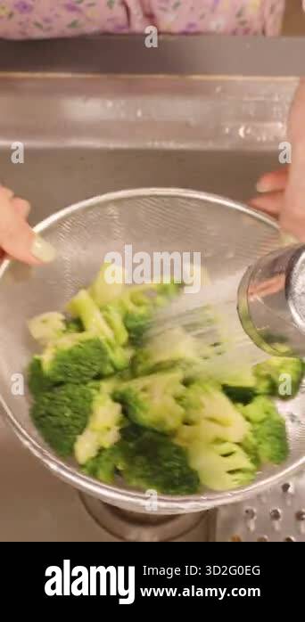 Vertical video. Overhead View of Woman Washing Steamed Broccoli in ...