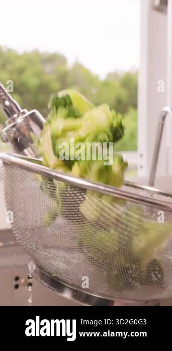 Vertical video. Hand Tossing Broccoli in Metal Strainer Above Sink in ...