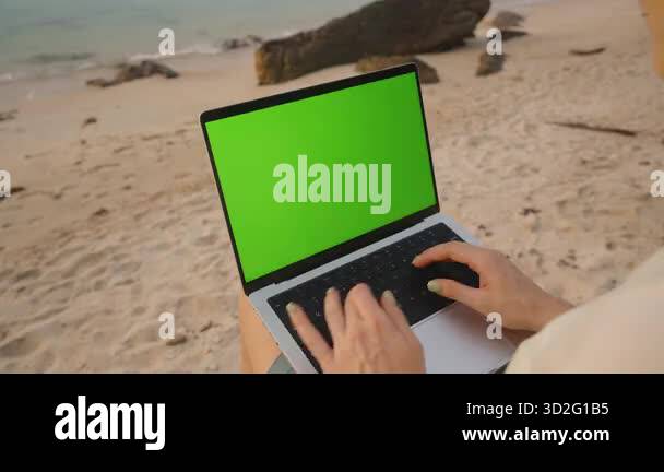 Close up of Hands Typing on Laptop with Green Screen on Sandy Beach, low angle, Remote Work ...