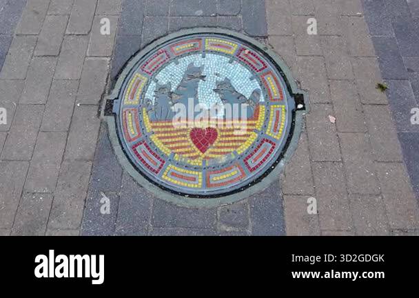 Round street cover with unique city emblem art on pavement adds charm ...