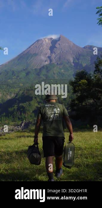A male adventurer goes solo camping, setting up a tent in the grass ...