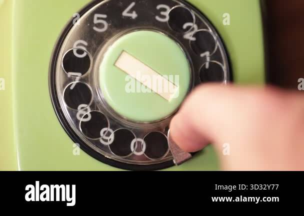 Close-up view of a hand dialing numbers on an old rotary phone. Retro ...