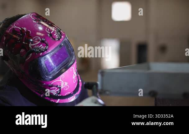 Expert welder with a protective pink mask who meticulously works on a ...