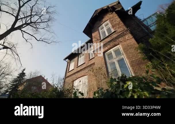 Old brick house stands tall against clear blue sky low angle shot. Two ...