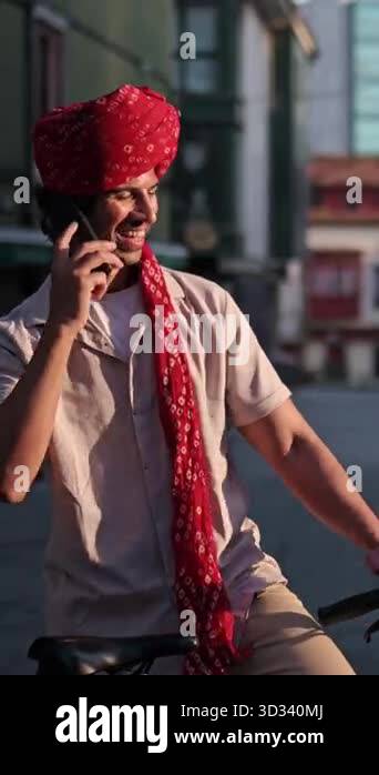 Smiling indian man wearing a traditional red turban, leaning on his ...