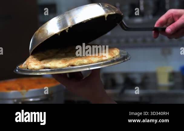 Professional chef carefully flips a large potato omelette using a metal ...